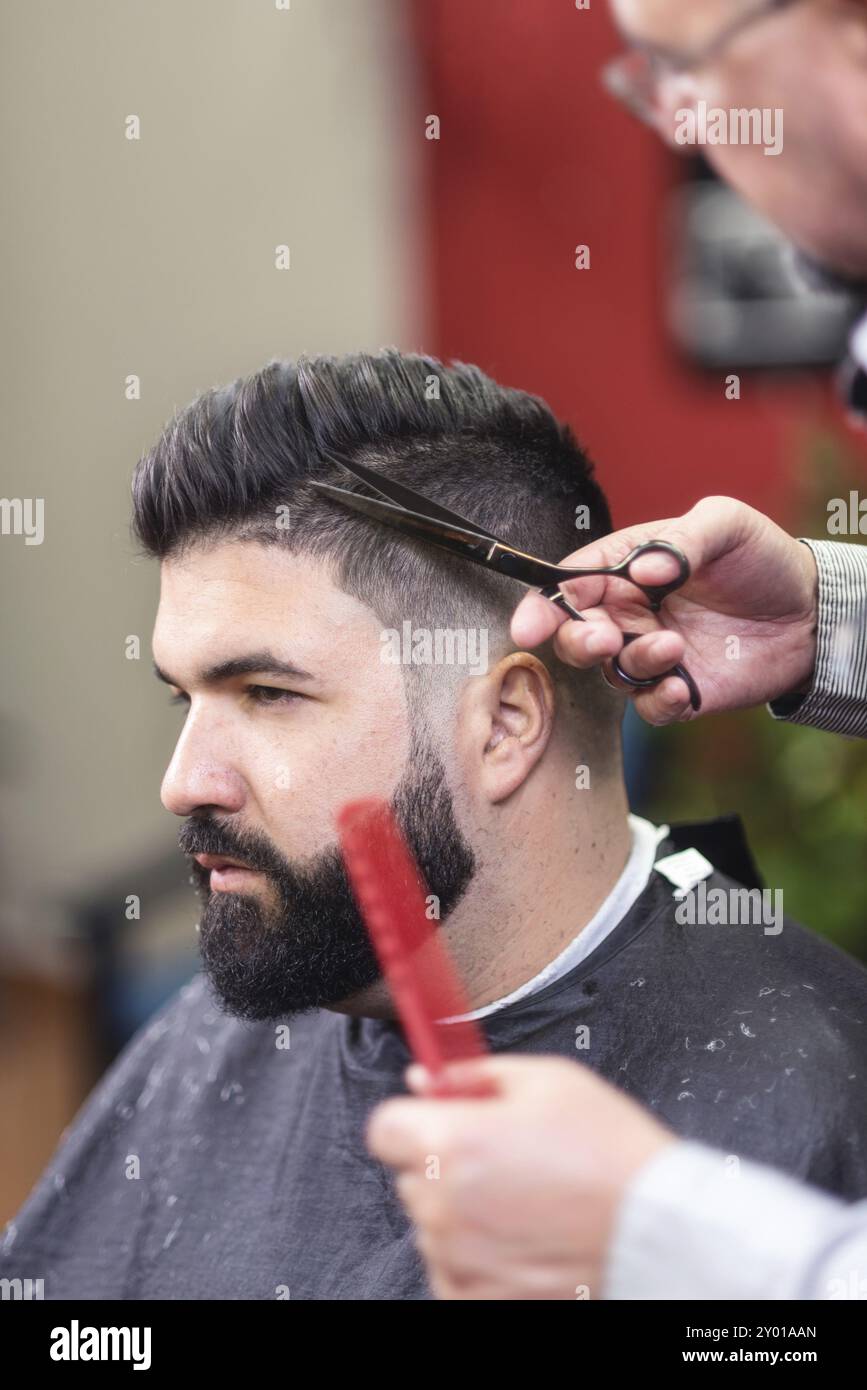 Handsome bearded man, having hair cut by scissors at barber shop Stock ...