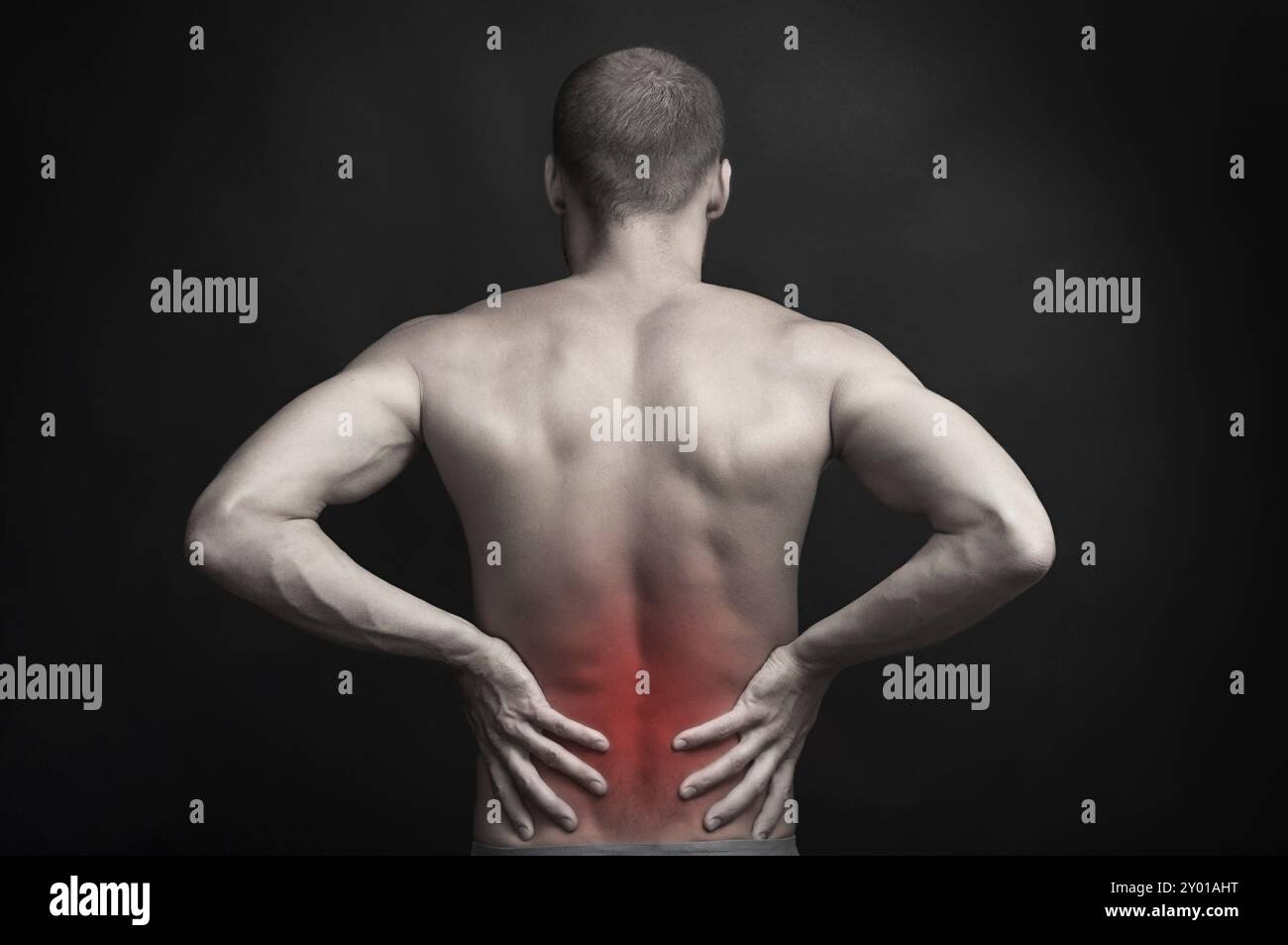 Strong muscular man holding his aching back with hands, spine ache ...