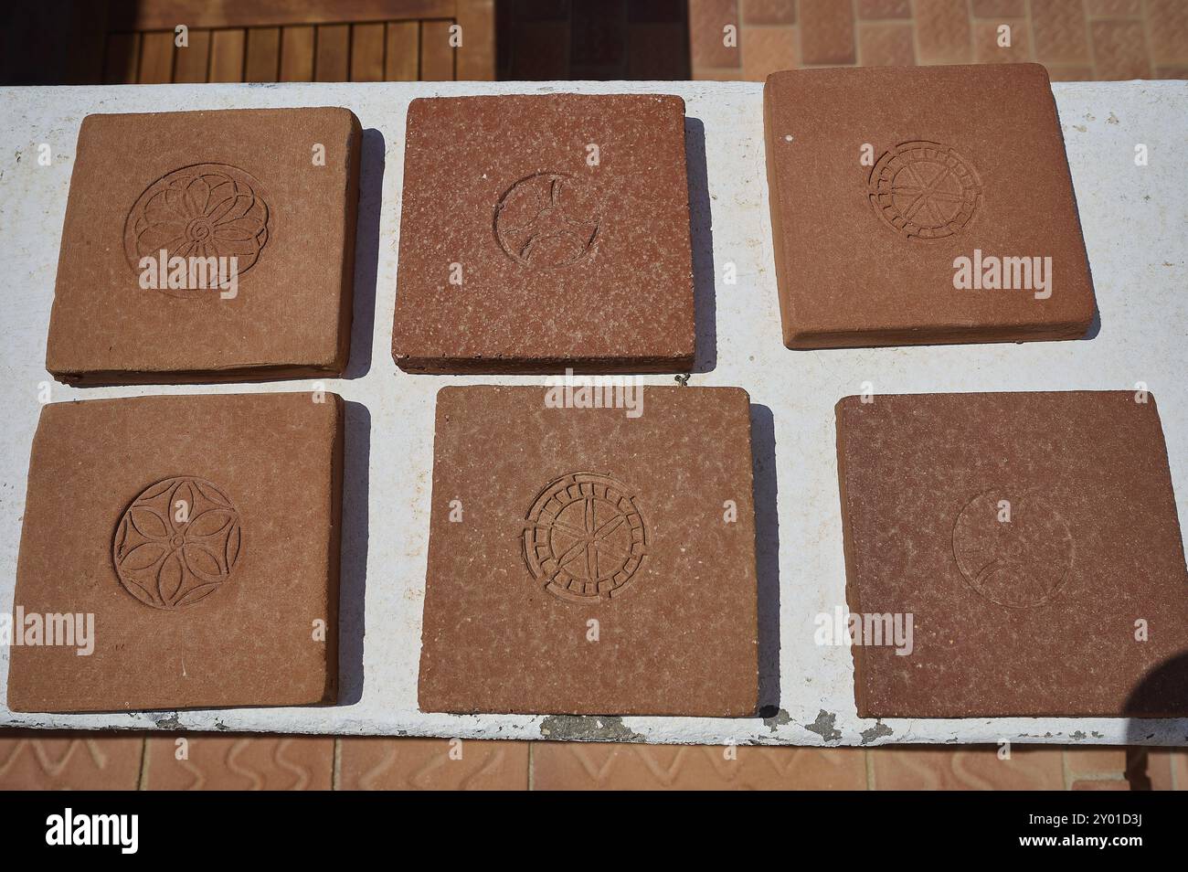 Six square clay bricks with different geometric and floral patterns ...