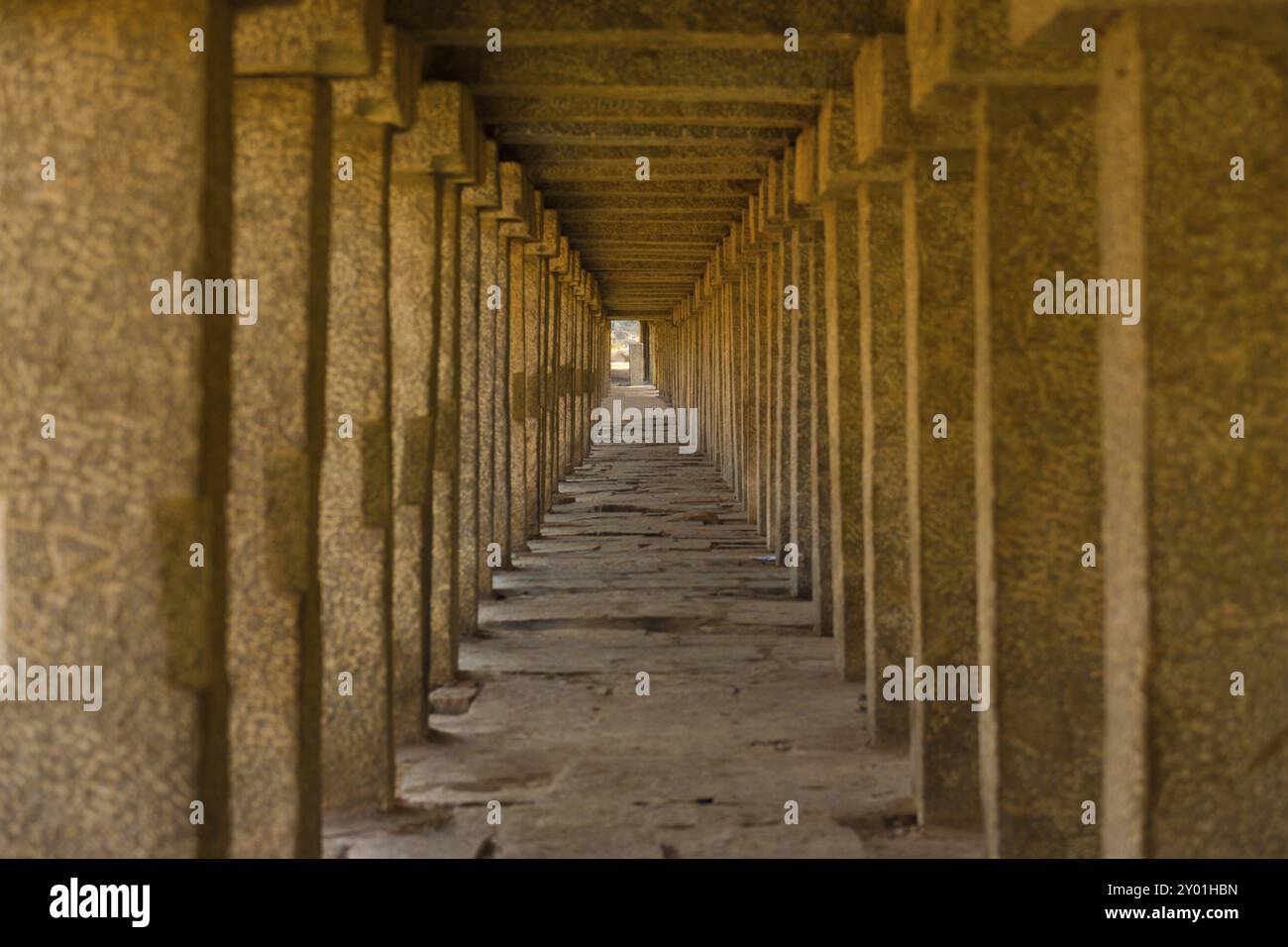 Stone columns repeat down a long covered walkway in the ancient ruins ...
