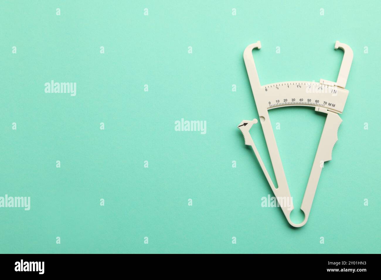 Plastic body fat caliper on turquoise background, top view. Space for ...