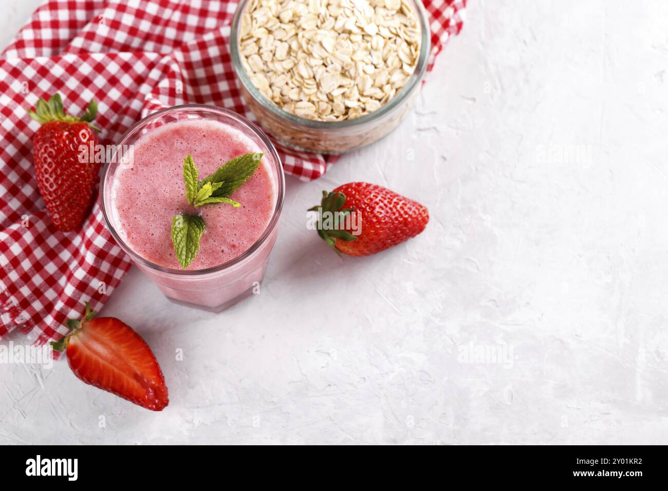 Strawberry milkshake or smoothie with oatmeal in a glass, top view copy ...