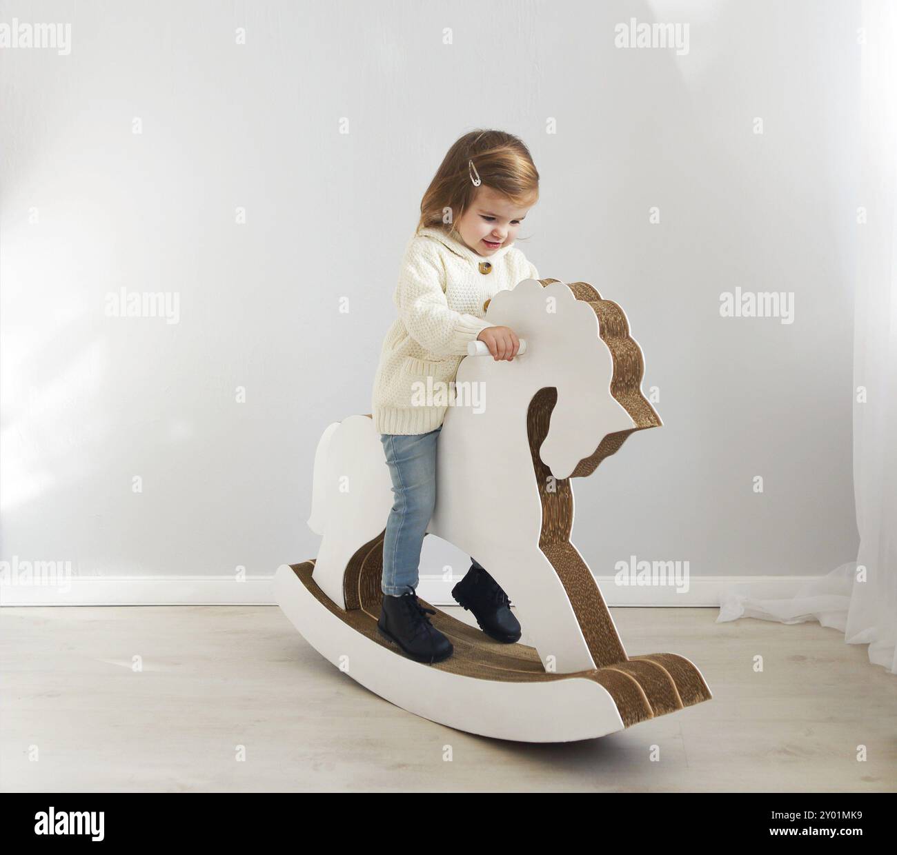 Adorable smiling toddler girl sitting on rocking horse Stock Photo - Alamy