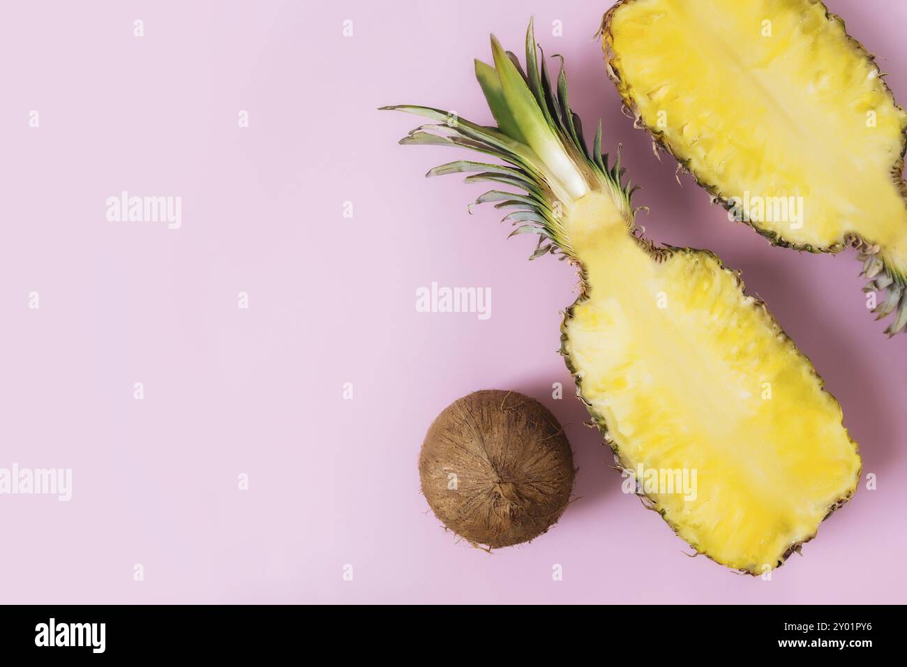 Flat lay with cut halves of fresh pineapple, coconut on a pastel pink ...