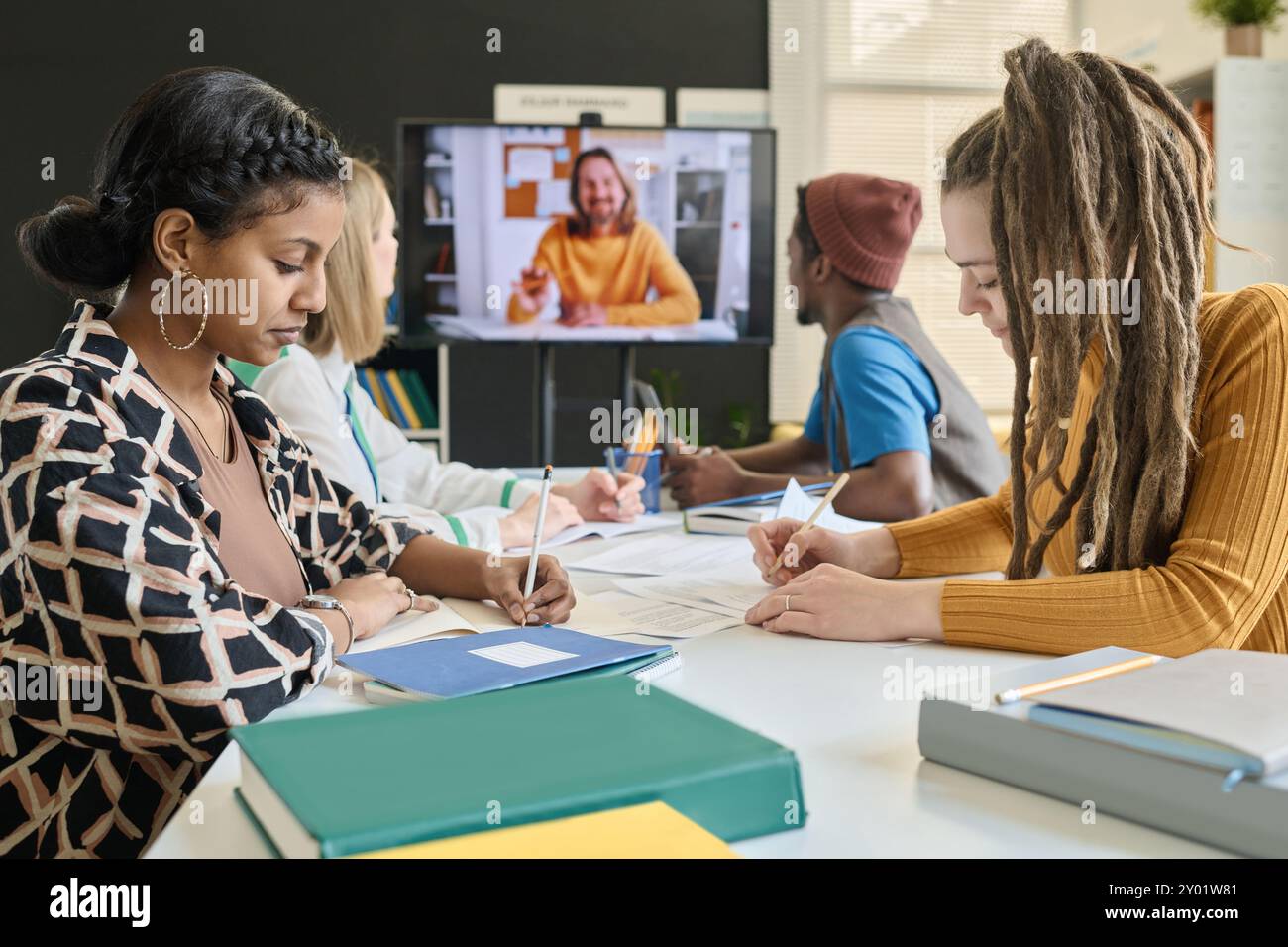 Multiethnic group of students watching video call with teacher speaking ...