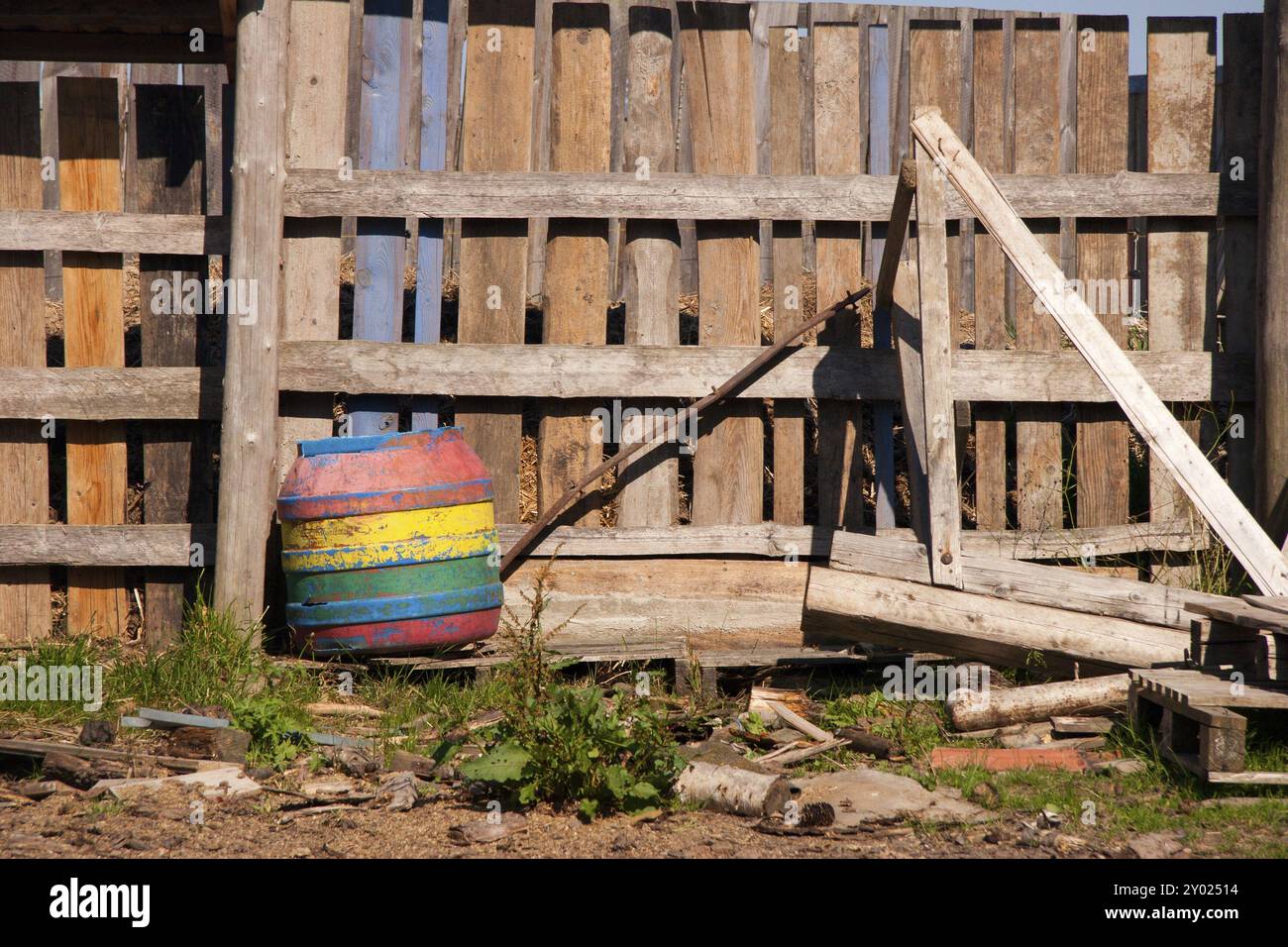 An old wooden fence with a colourful rain barrel An old wood fence with ...