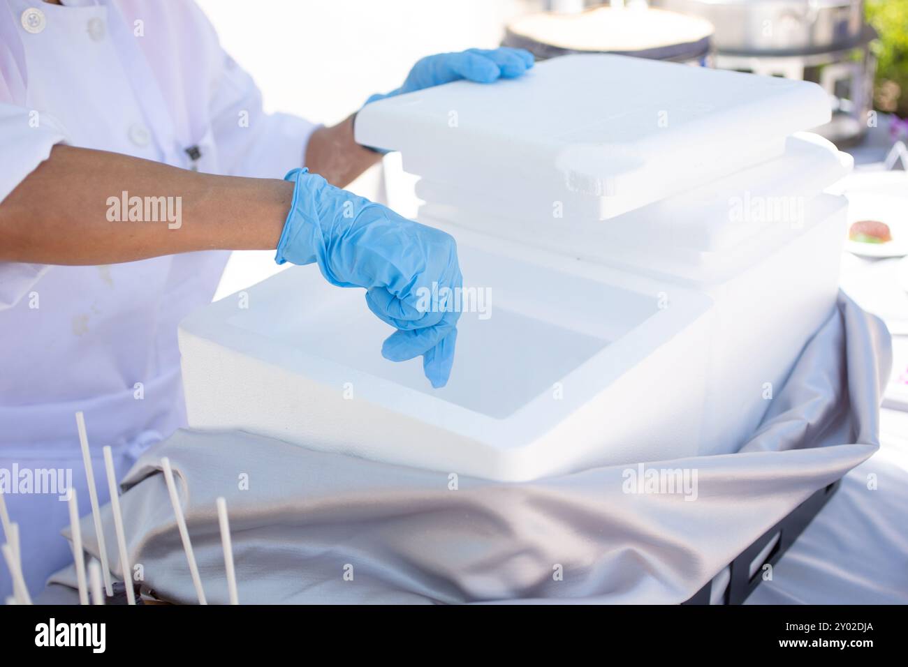 A view of a chef dipping food on a stick into a styrofoam chamber of ...