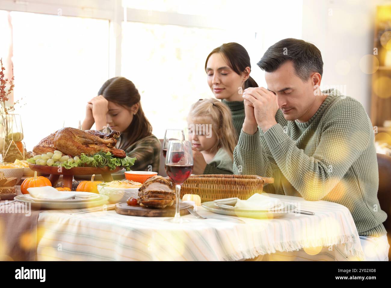 Family praying before dinner at festive table on Thanksgiving Day Stock ...
