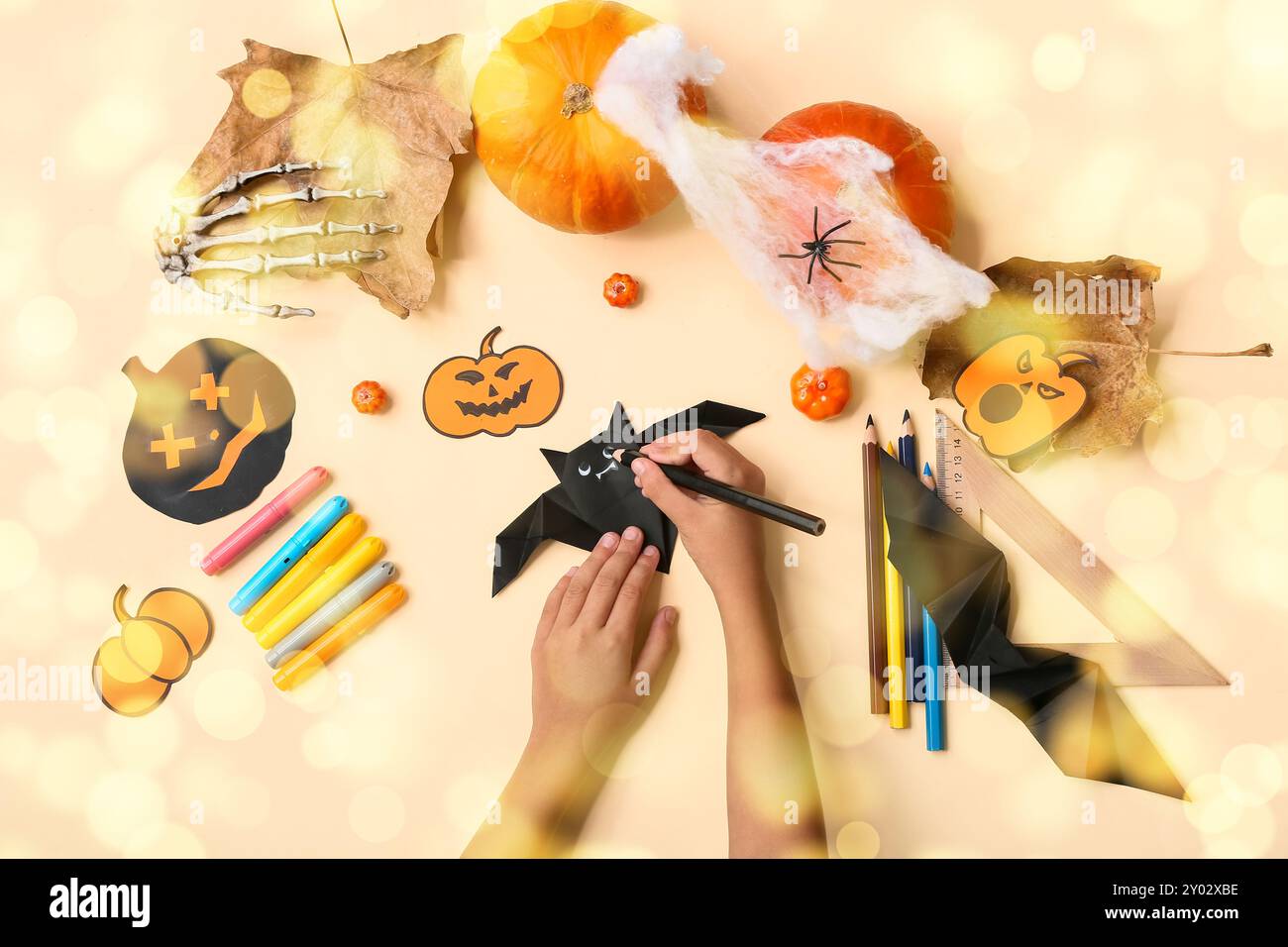 Hands of child making decorations for Halloween celebration on beige ...
