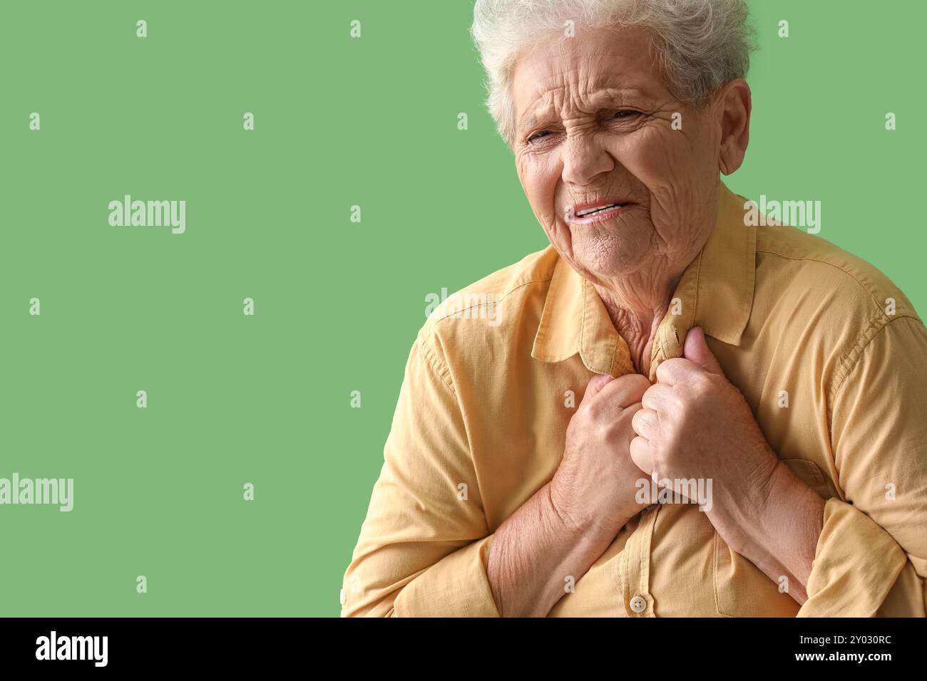Elderly woman having heart attack on green background Stock Photo - Alamy