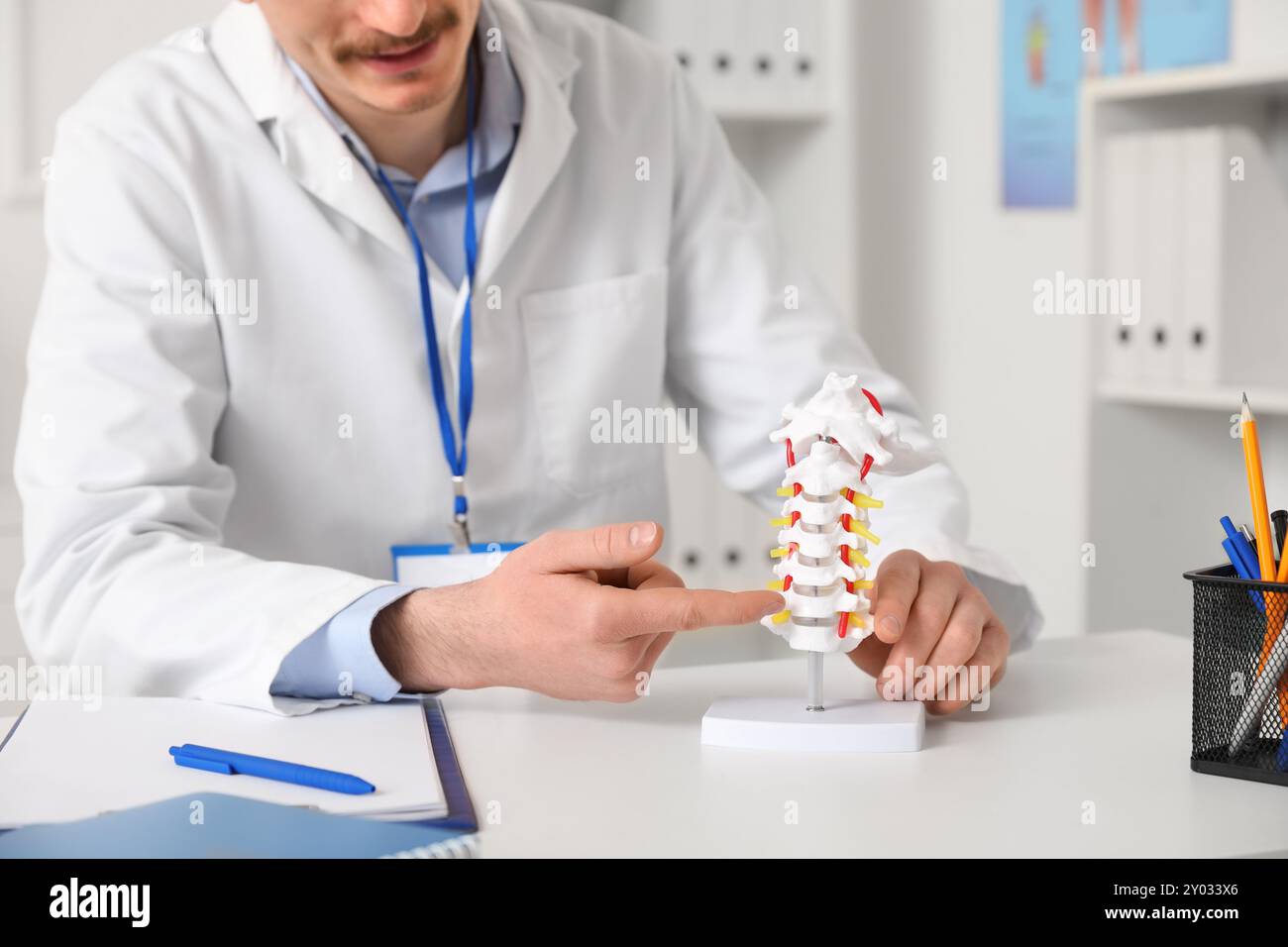 Male doctor demonstrating spinal anatomy with vertebral column model in ...