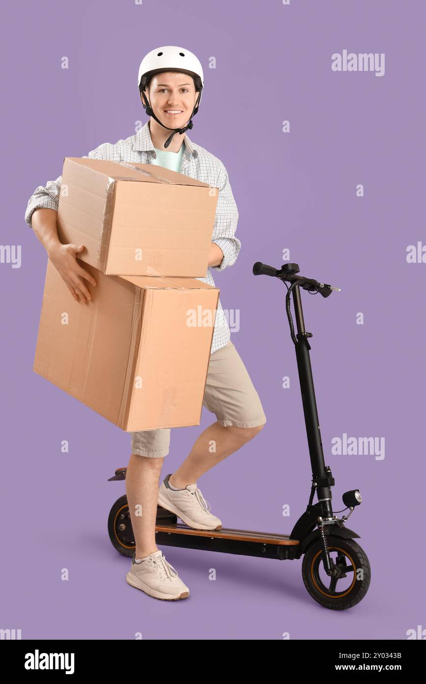 Male courier with big cardboard boxes and kick scooter on lilac ...