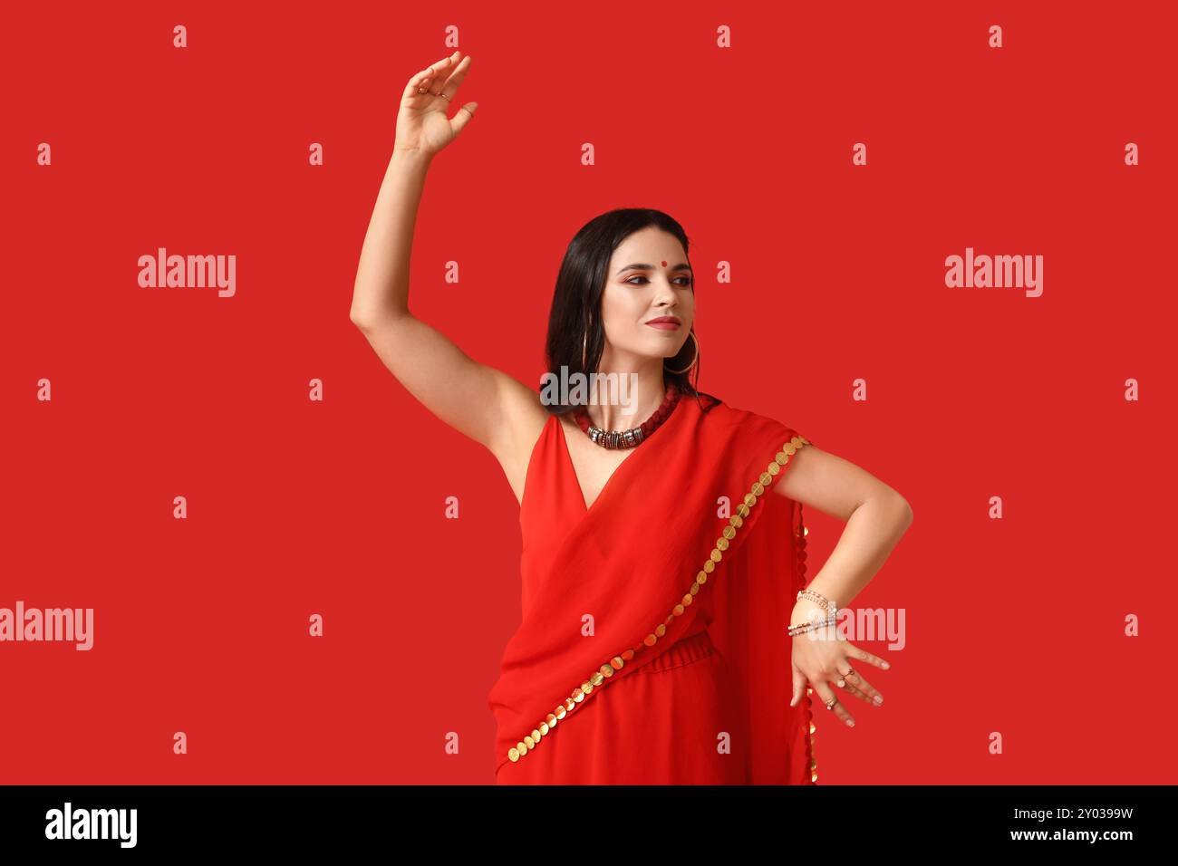 Beautiful young happy Indian woman in traditional sari dancing on red ...