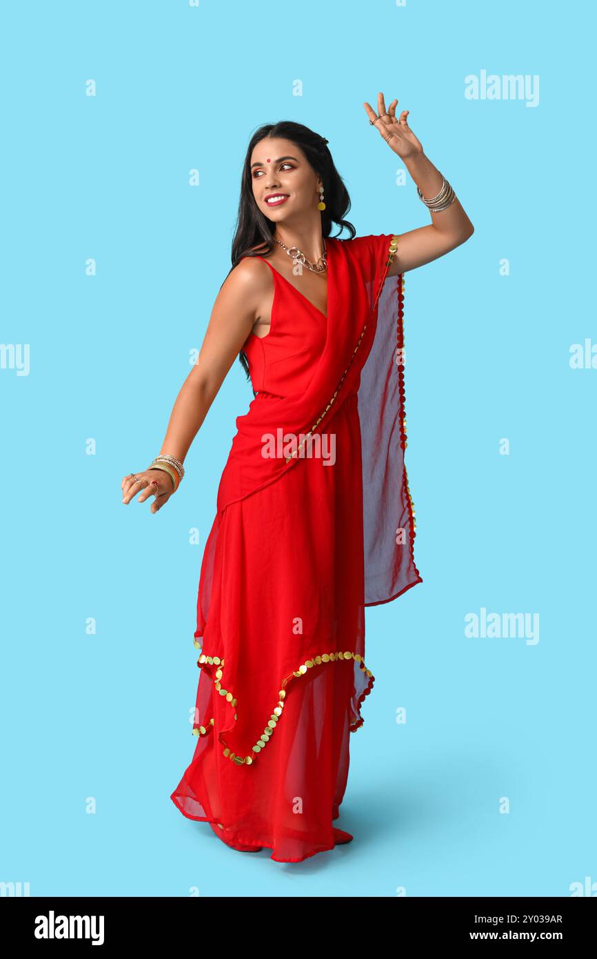 Beautiful young happy Indian woman in traditional sari dancing on blue ...