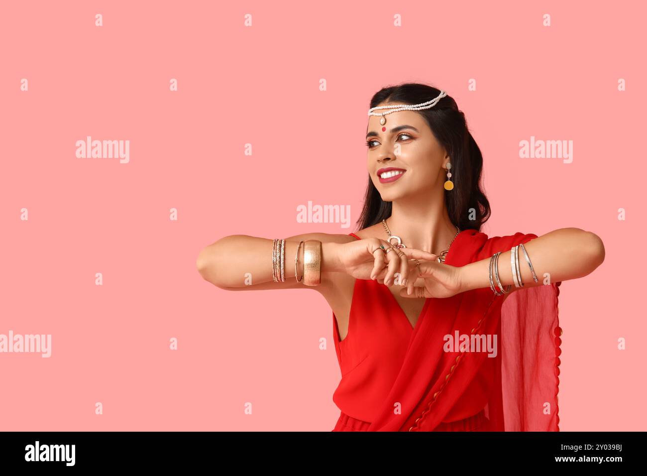 Beautiful young happy Indian woman in traditional sari dancing on pink ...
