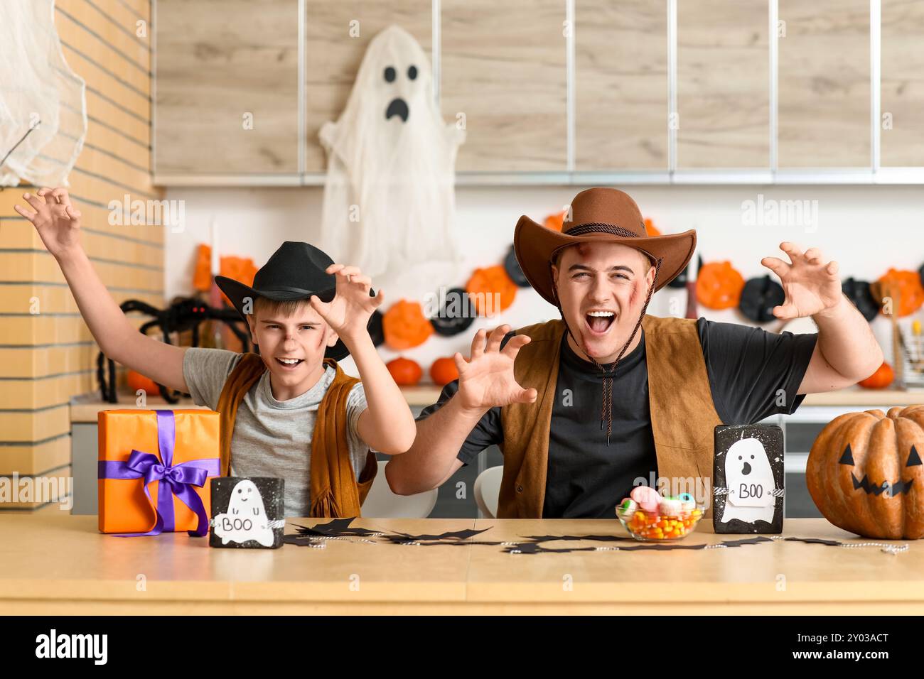 Scary father with his son dressed for Halloween as cowboys in kitchen ...