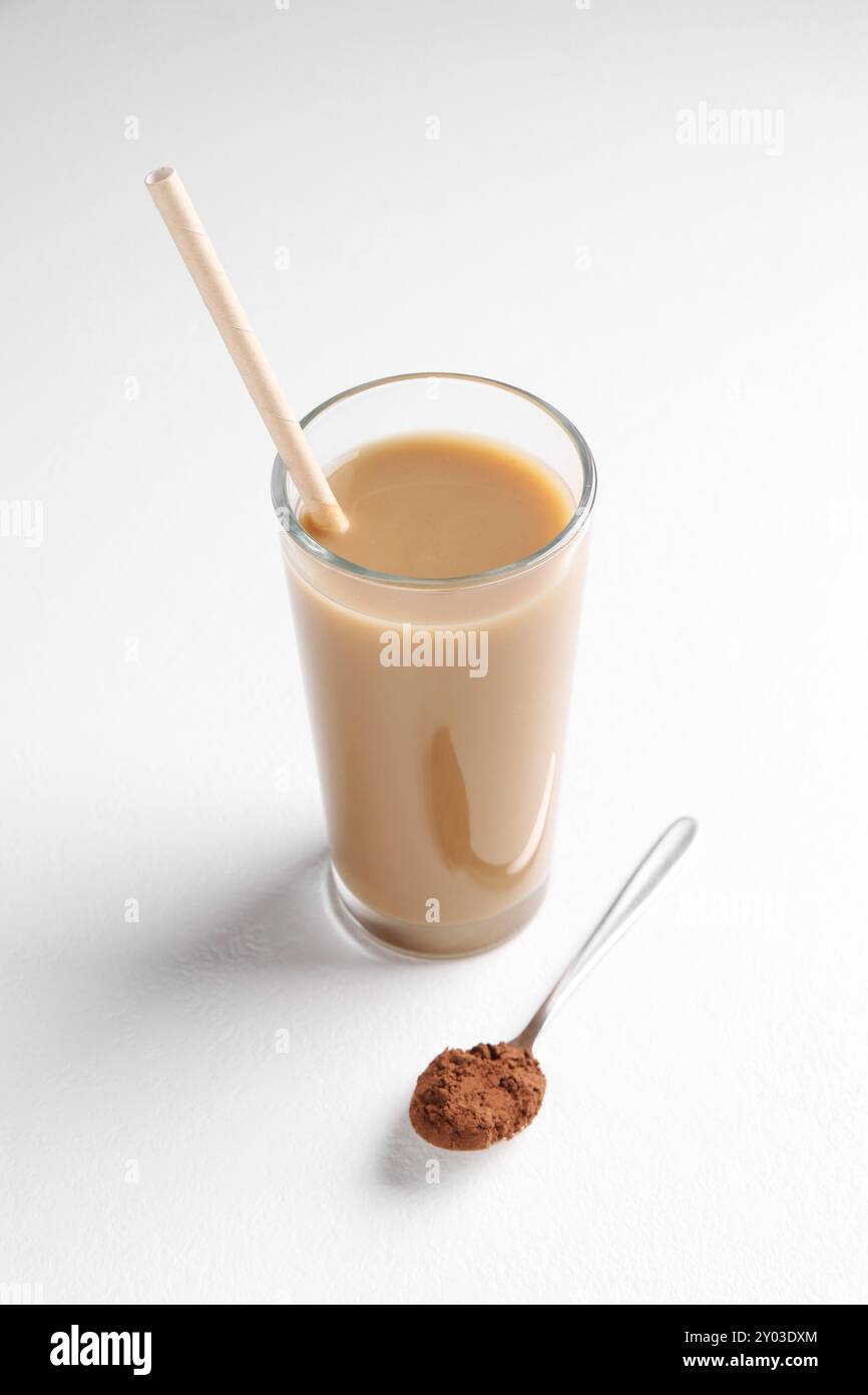 Delicious protein shake in glass and spoon with powder on white ...