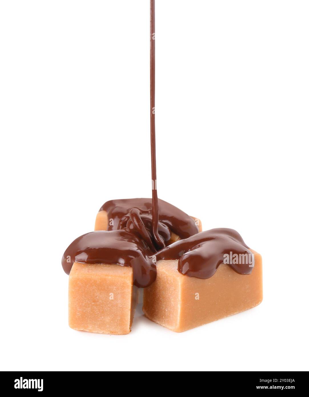 Pouring tasty melted chocolate onto caramel candies on white background ...