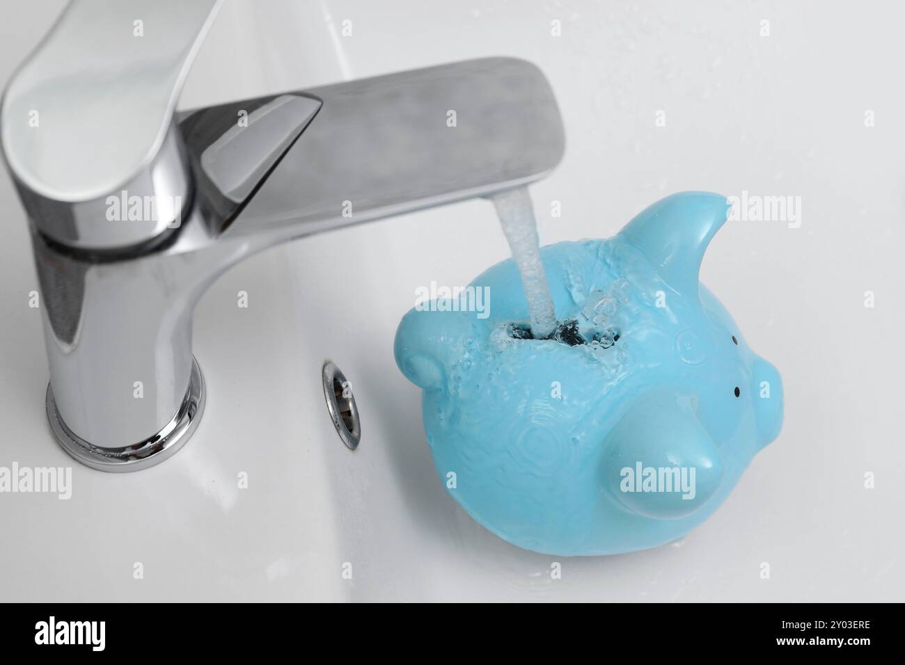 Water saving concept. Stream of water flowing from tap into piggy bank ...