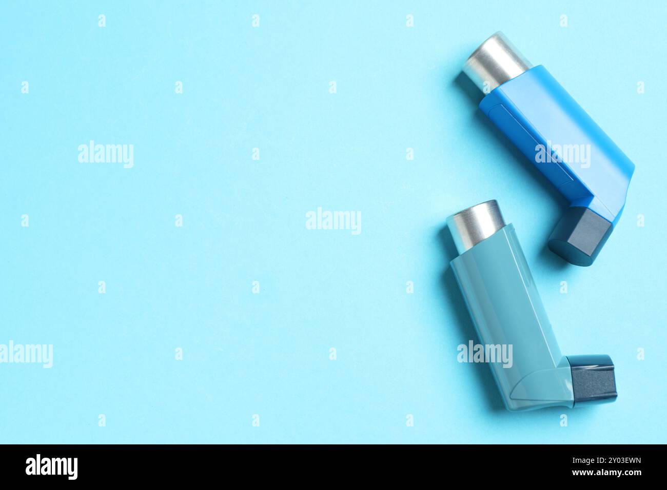 Asthma inhalers on light blue background, flat lay. Space for text ...