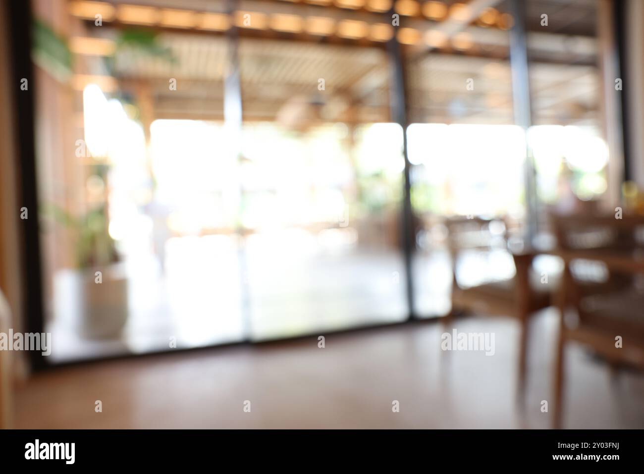 Blurred view of cafeteria with large windows and comfortable furniture ...