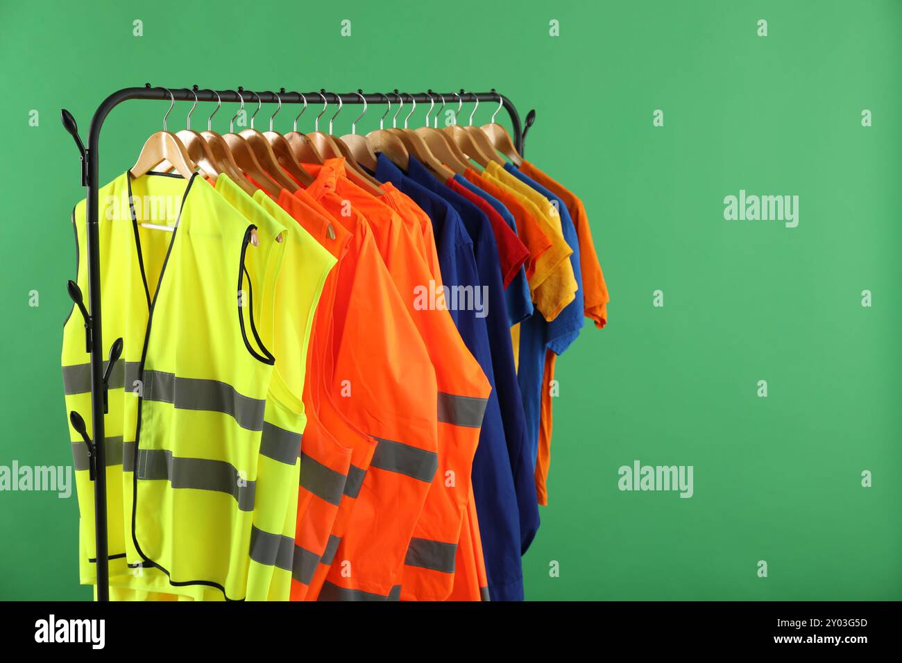 Different workers' uniforms and reflective vests on clothing rack ...