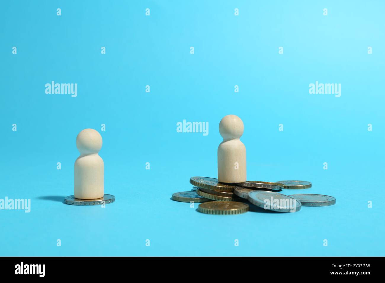 Financial inequality. One wooden figure on bigger pile of coins than ...