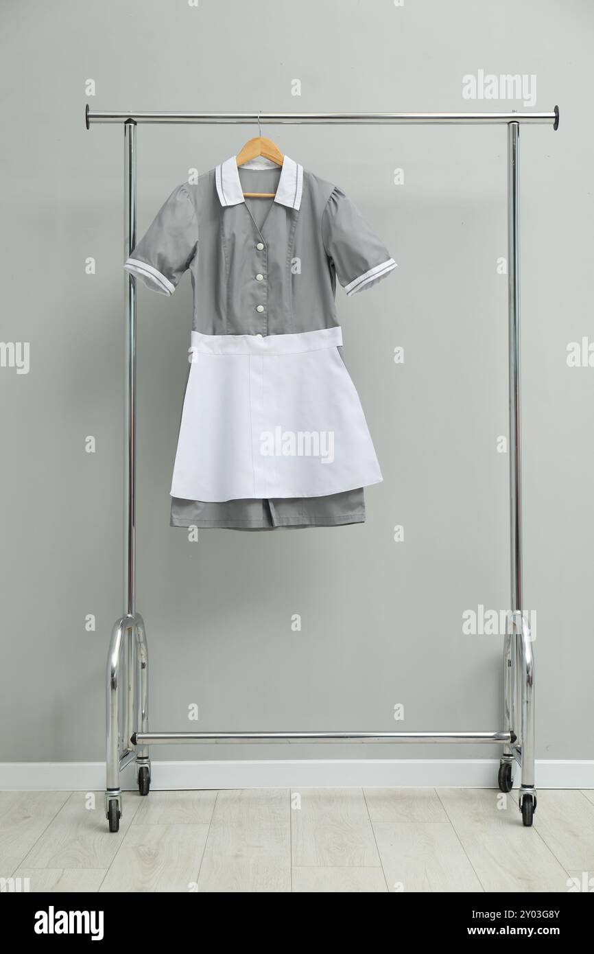 Maid's uniform on clothing rack near grey wall indoors Stock Photo - Alamy