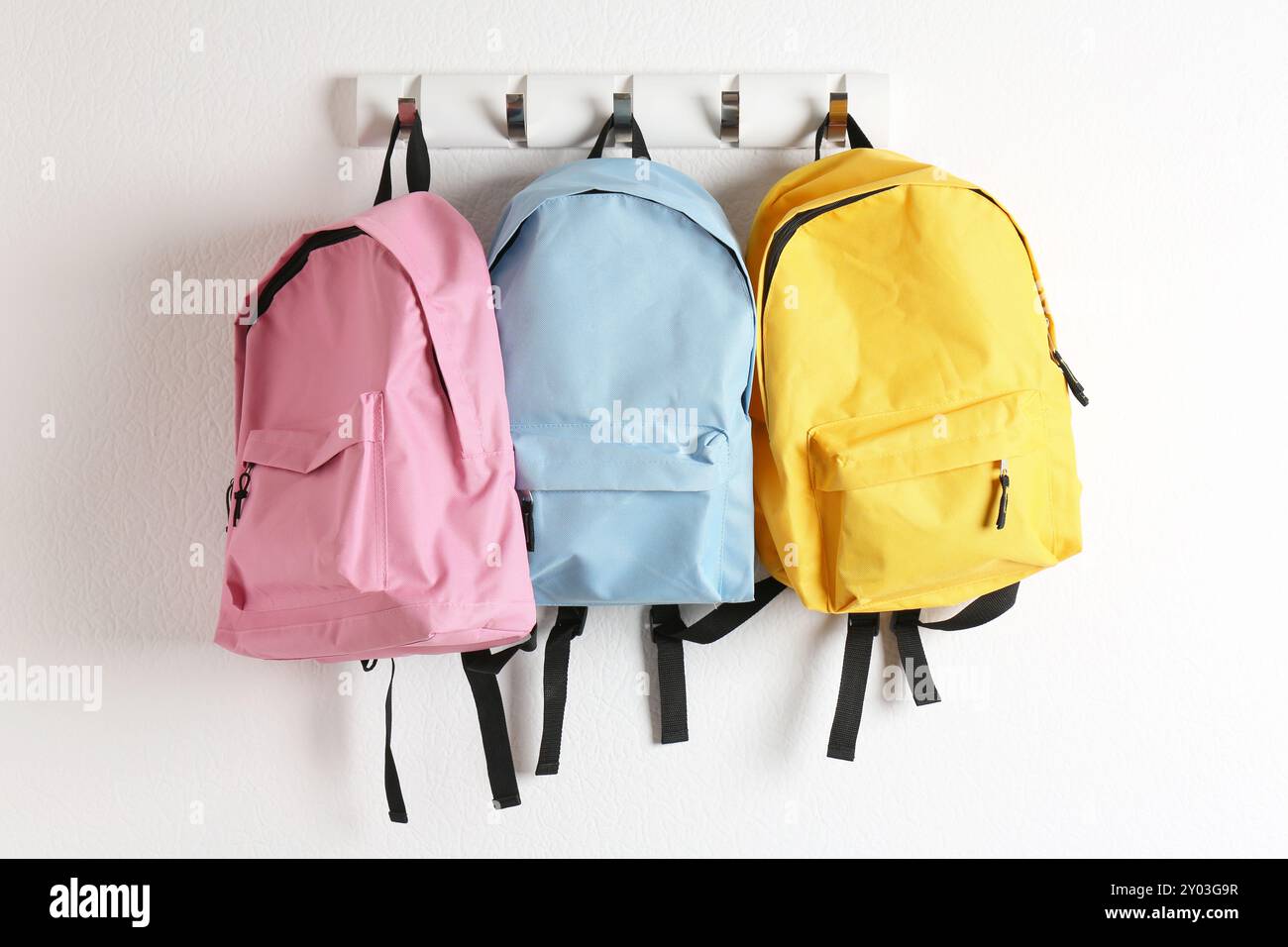Bright backpacks hanging on white wall. Back to school Stock Photo - Alamy