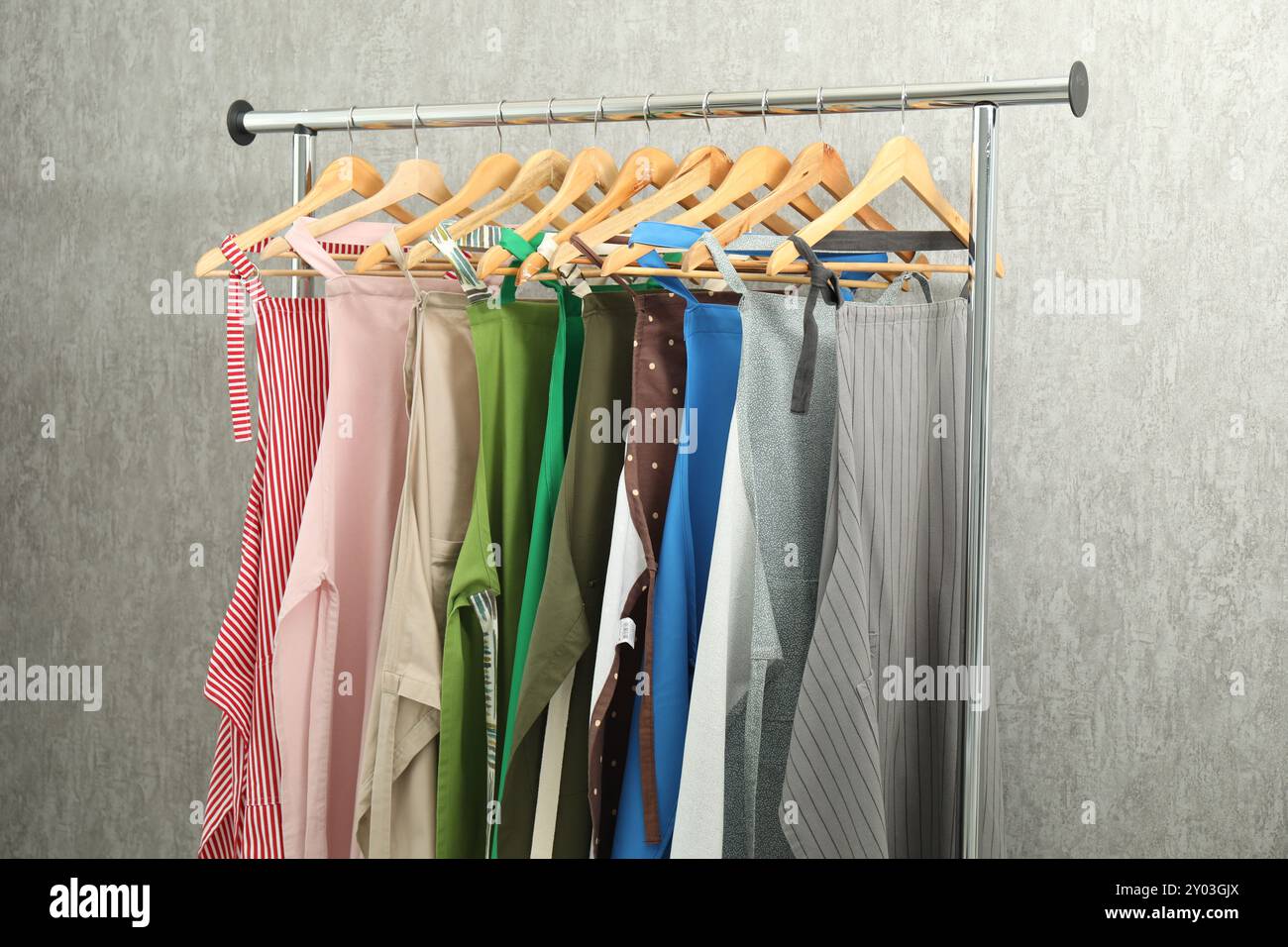 Aprons on clothing rack near light grey wall Stock Photo - Alamy