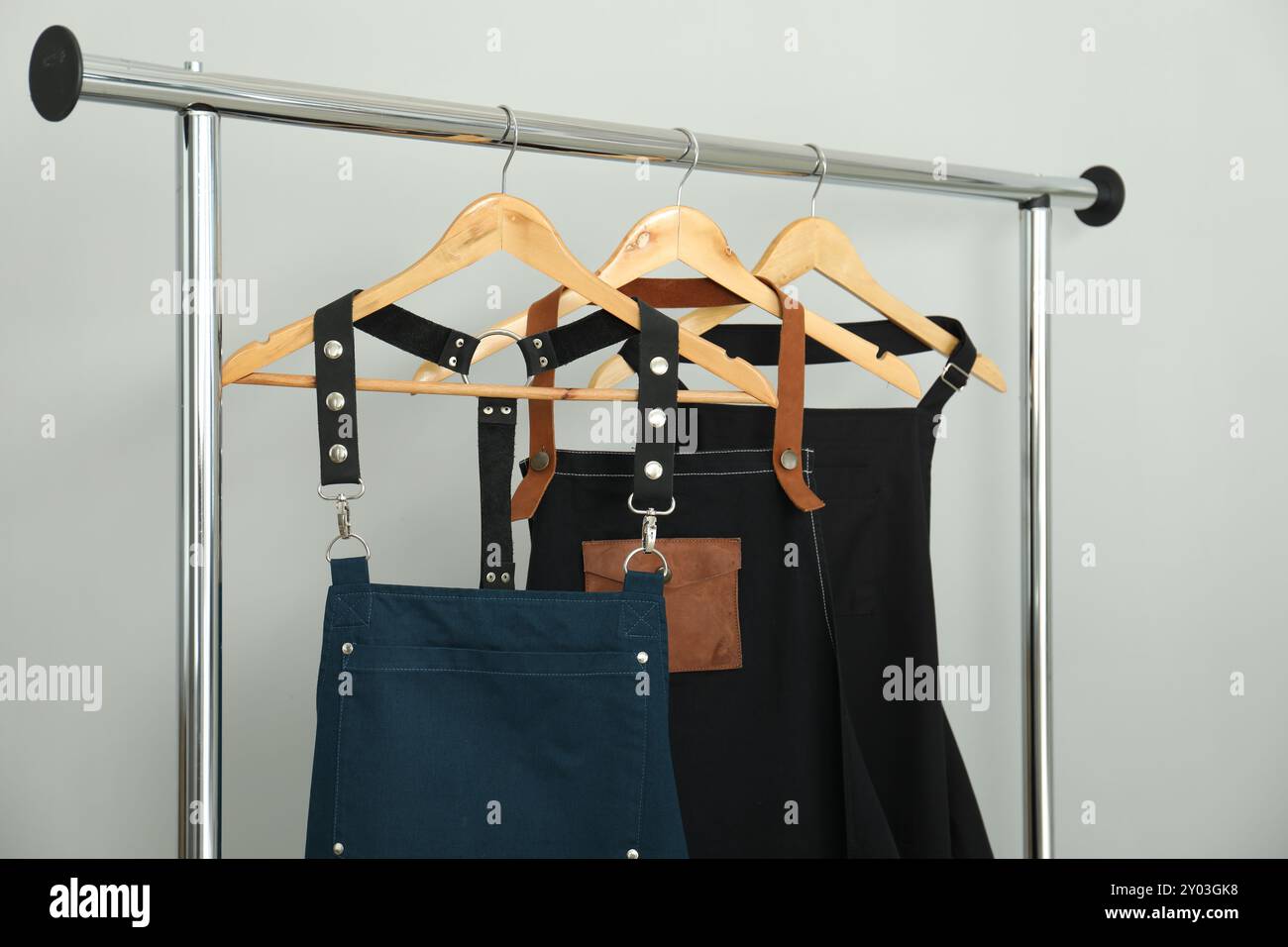 Aprons on clothing rack near light grey wall Stock Photo - Alamy