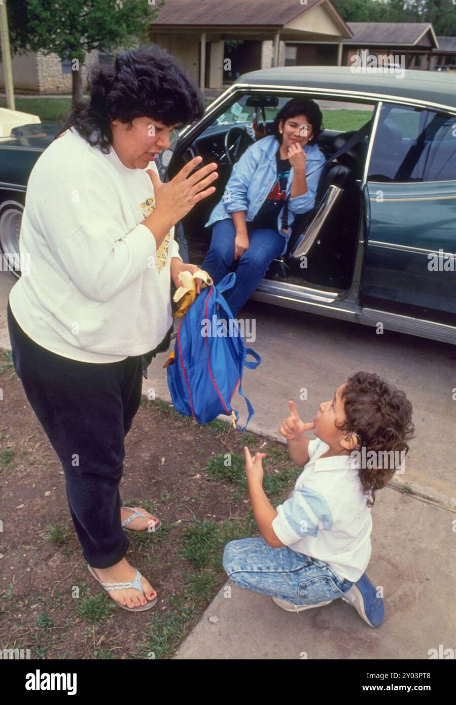 Deaf kindergarten child signs to his mother outside of their house in ...