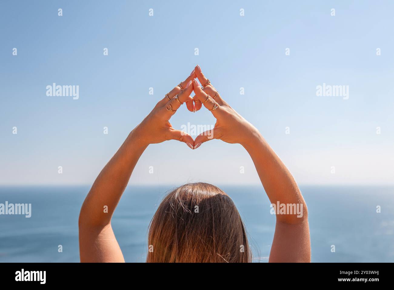 A woman is holding her hands together in a heart shape, with her arms ...