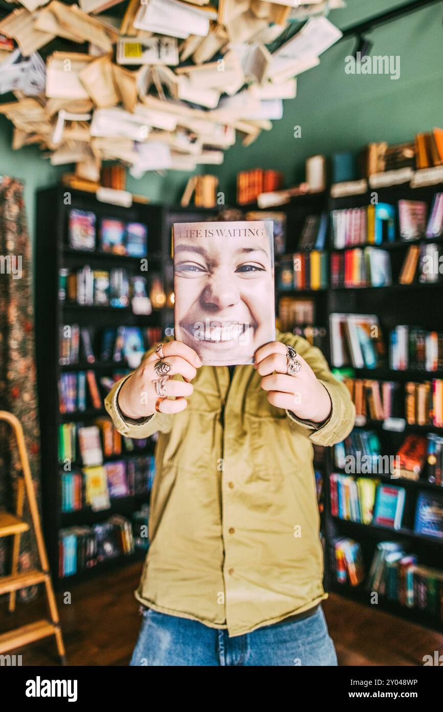 Young man showing book cover while standing in bookstore Stock Photo ...