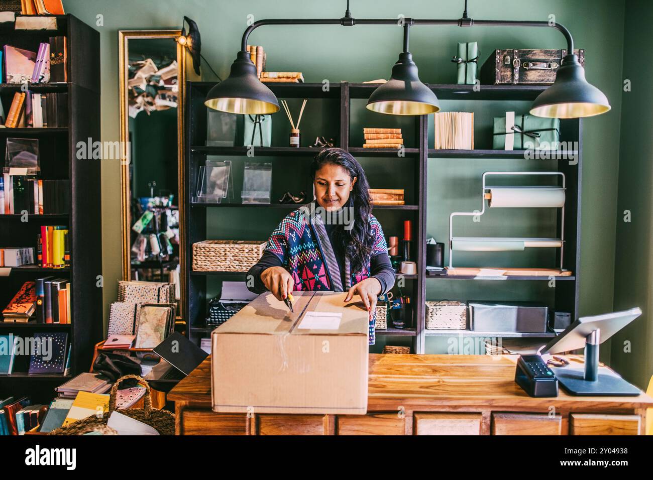 Female shop owner opening cardboard box at checkout in store Stock ...