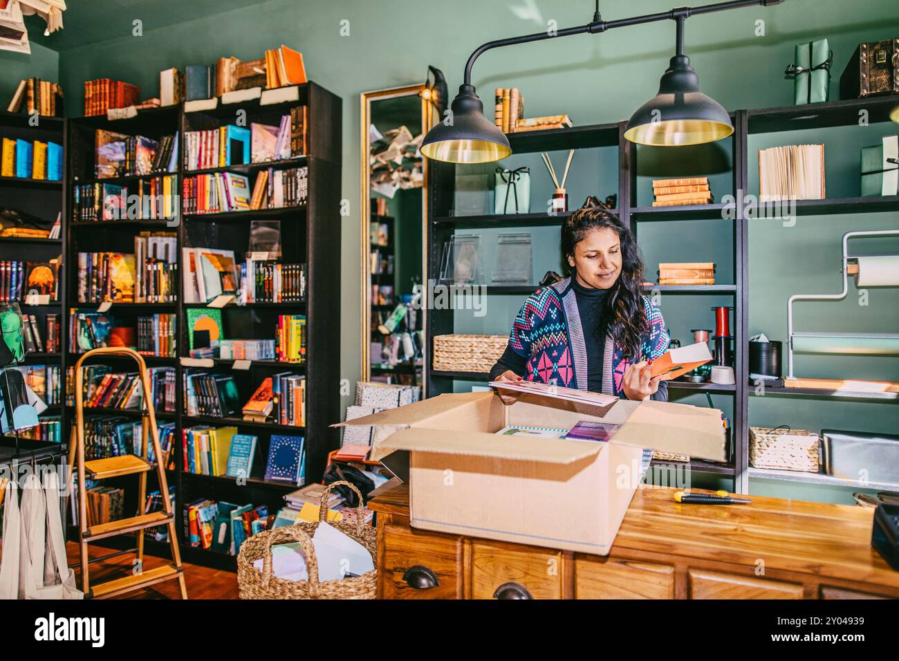 Female owner unpacking new books from cardboard box in store Stock ...