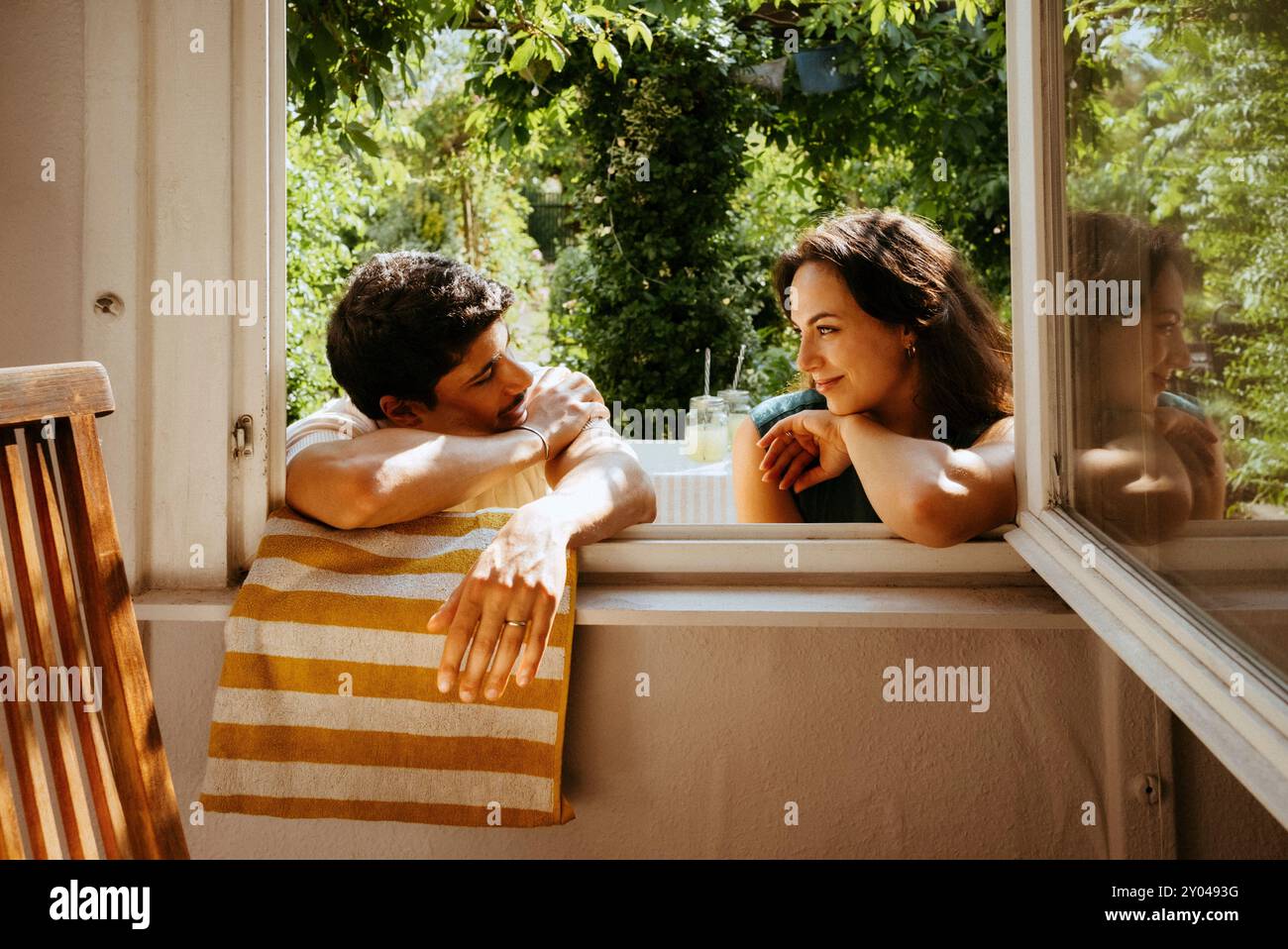 Romantic multiracial young couple leaning on window during dinner party ...