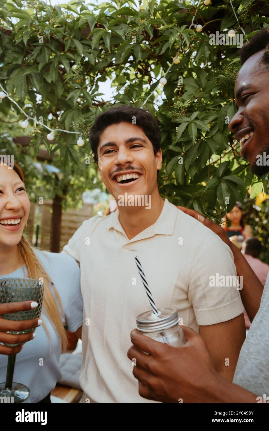 Happy young man with friends enjoying drinks in back yard during dinner ...