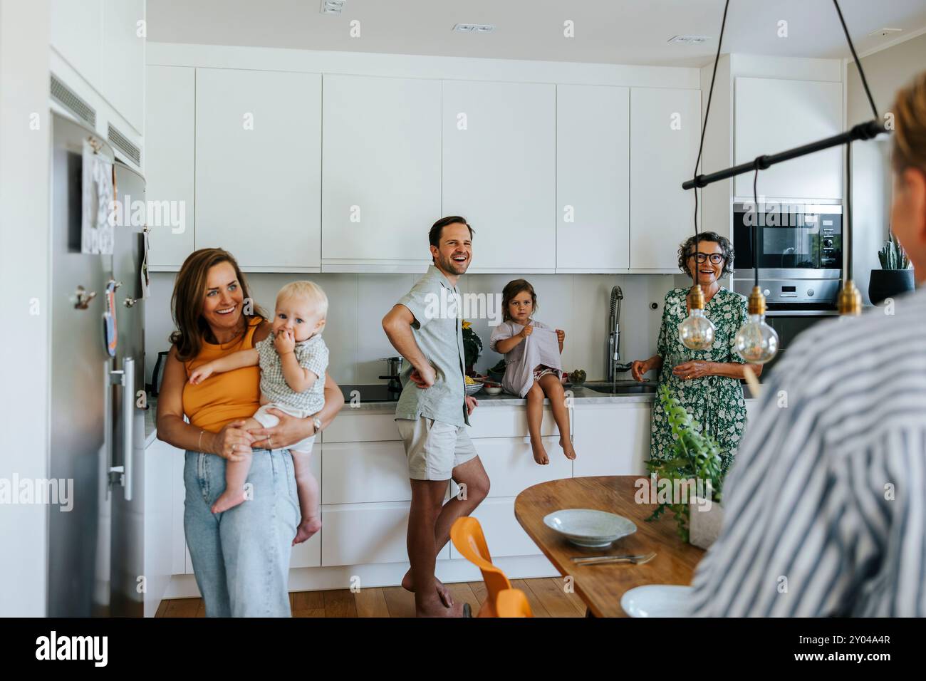Happy multi-generational family laughing while talking with each other ...