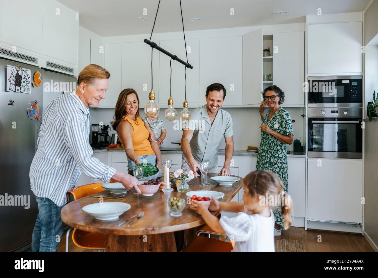 Happy multi-generational family helping each other in setting dining ...