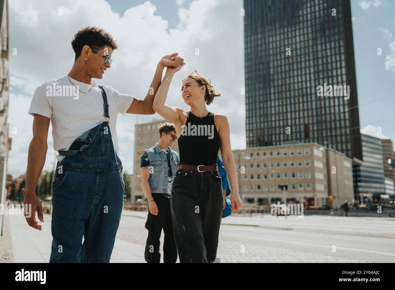 Fashionable young man dancing with female friend while walking on ...