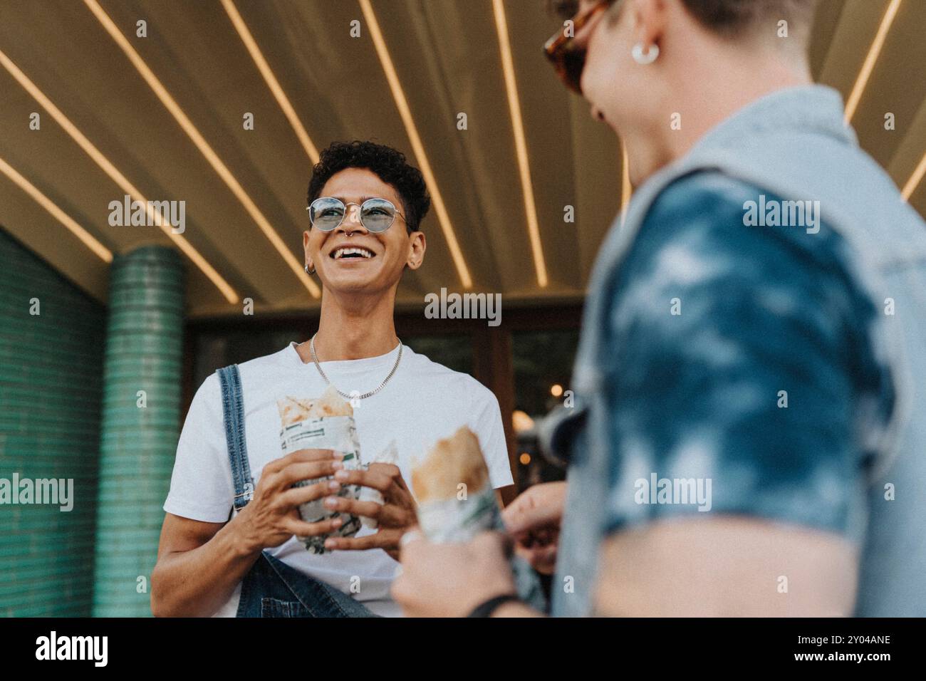 Happy young man in sunglasses holding wrap sandwich and standing with ...