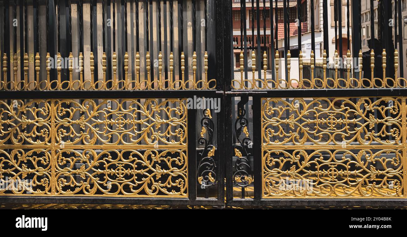 Iron gates with intricate floral and swirl details. House facade ...