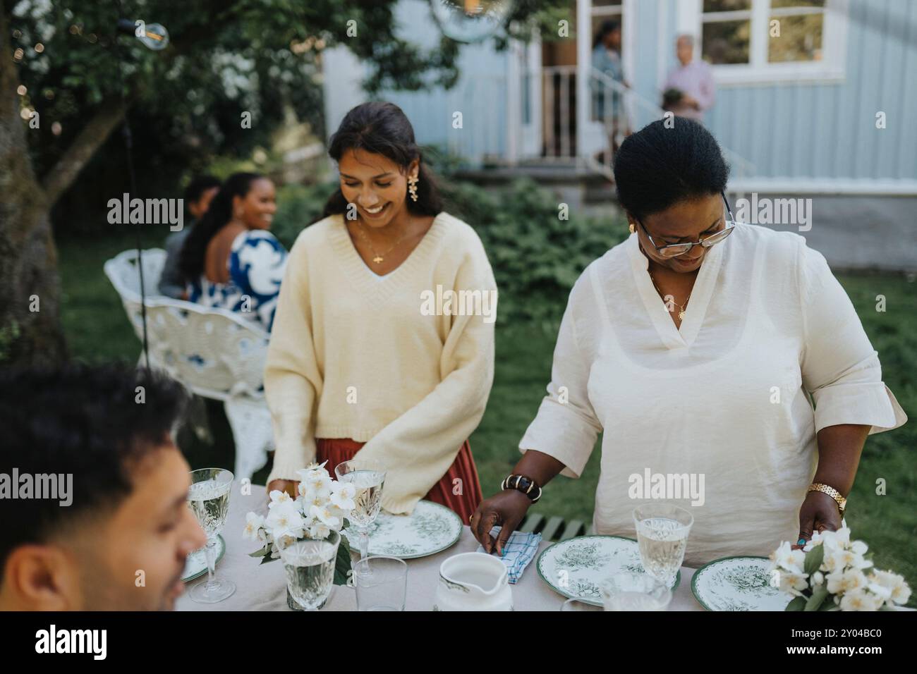 Female family members setting table for dinner during social gathering ...