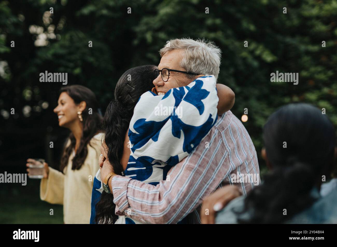 Happy senior man hugging female family member during social gathering ...