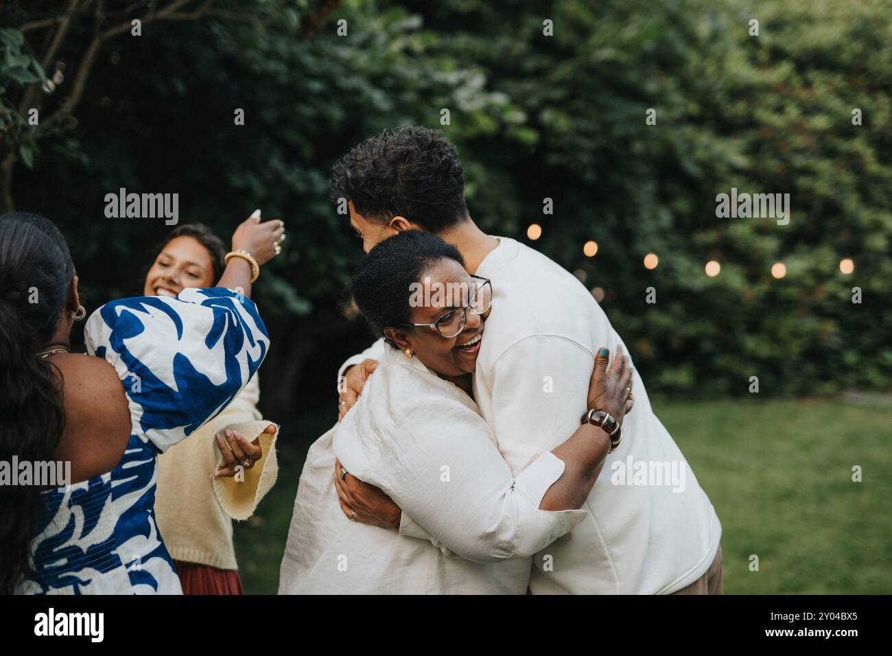 Happy senior woman hugging male family member during social gathering ...