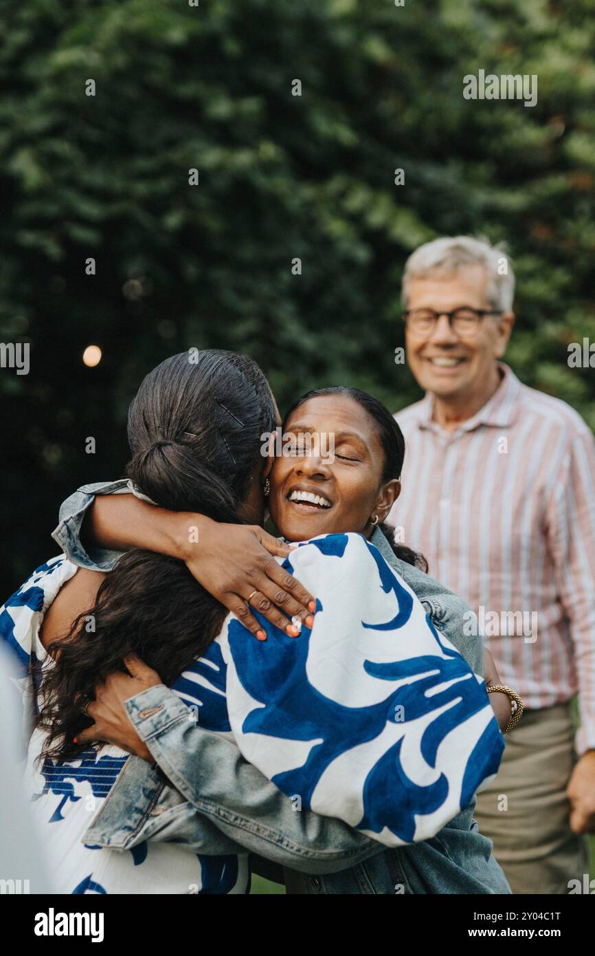 Female family members hugging each other at social gathering in back ...