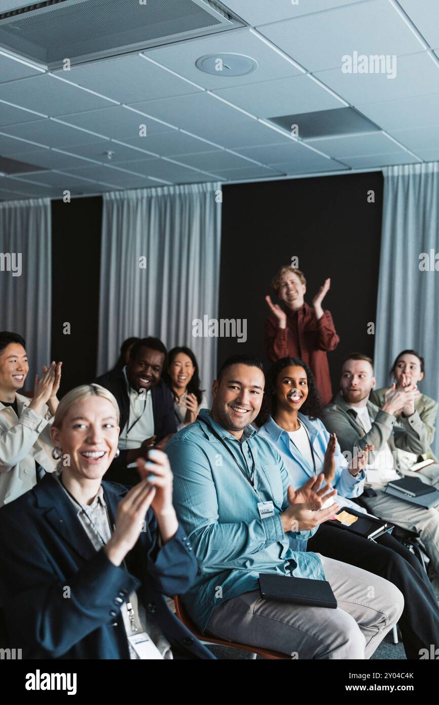 Smiling male and female entrepreneurs clapping while sitting together ...