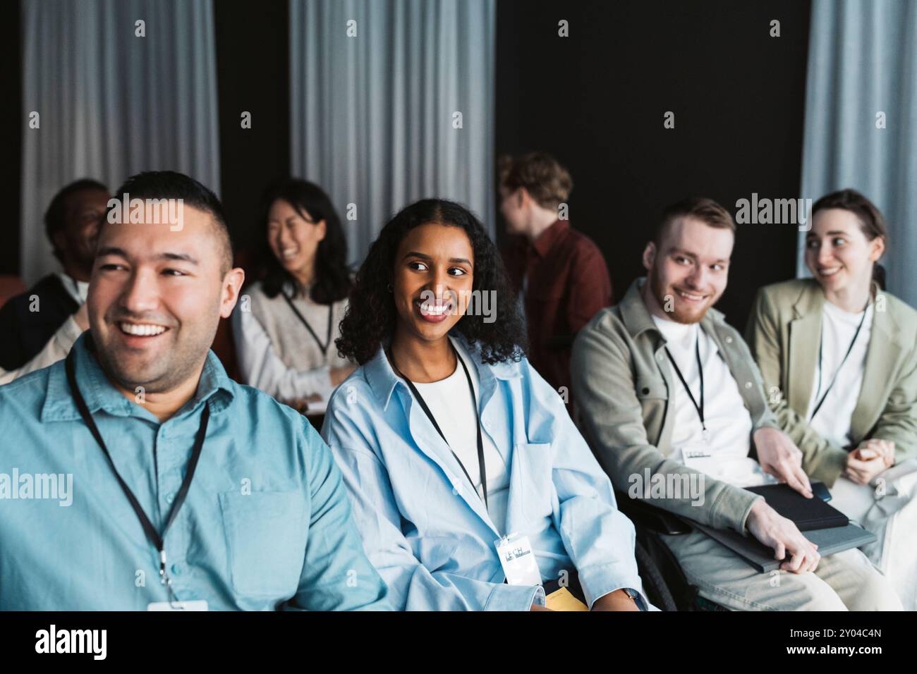 Smiling male and female delegates sitting side by side in seminar at ...