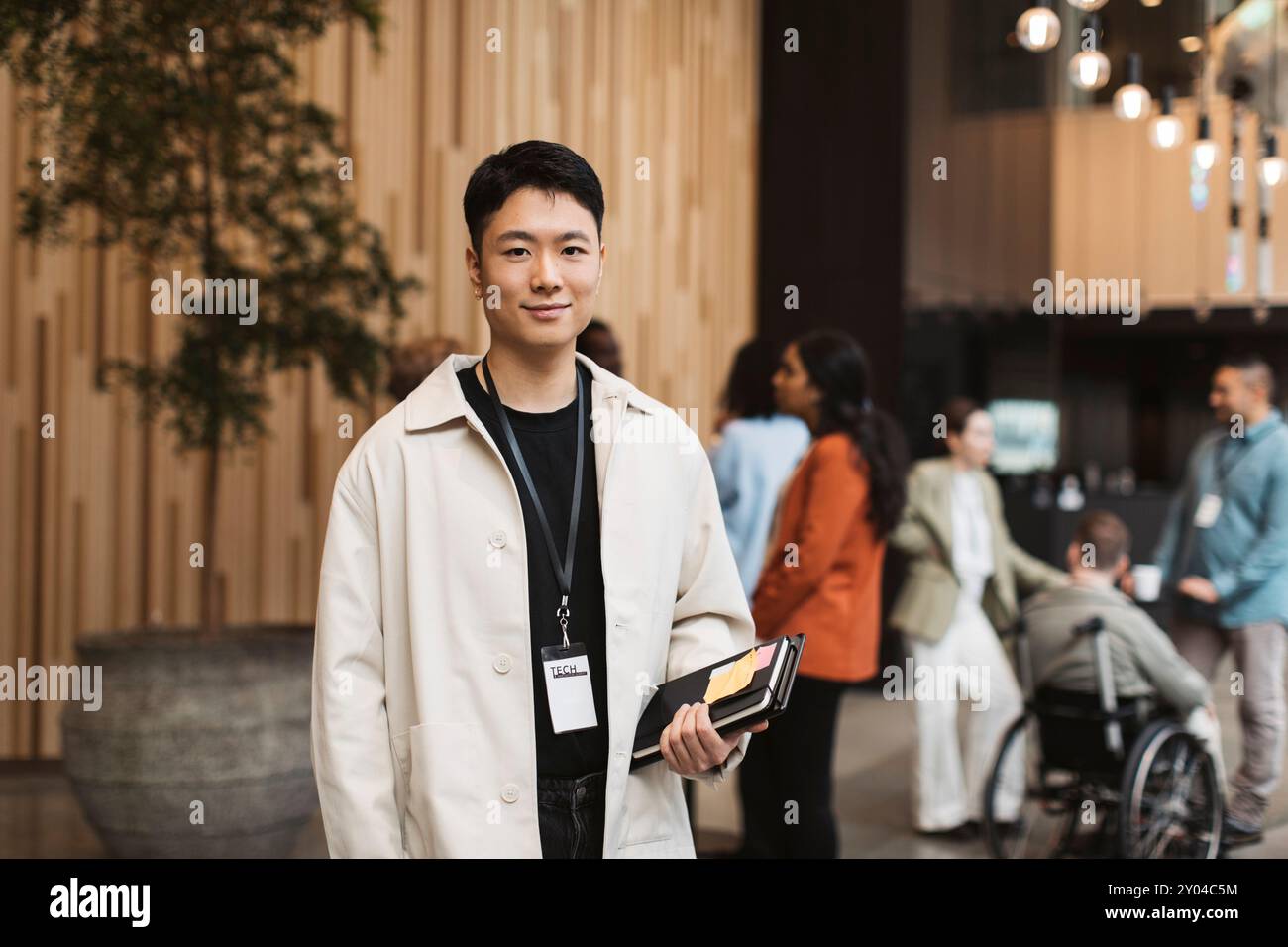 Portrait of confident young male entrepreneur holding diary while ...